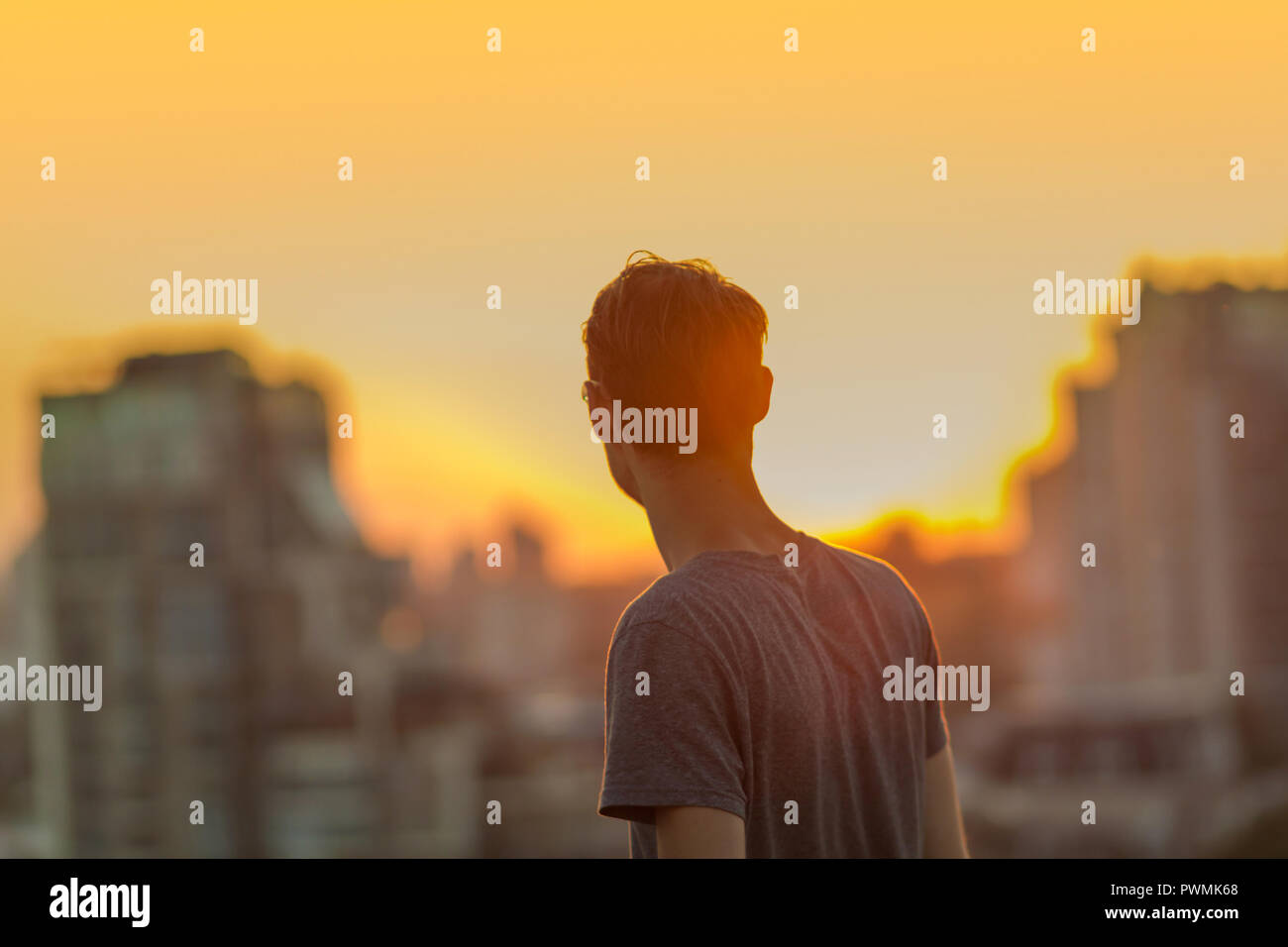 Defocused cityscape background. Gorgeous warm bokeh. Man on the sunset ...