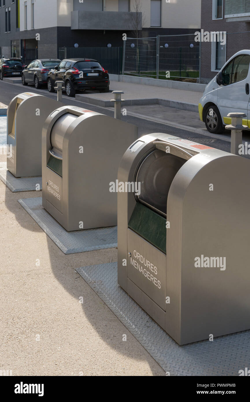 Sorting out garbage containers burried in the street Stock Photo - Alamy