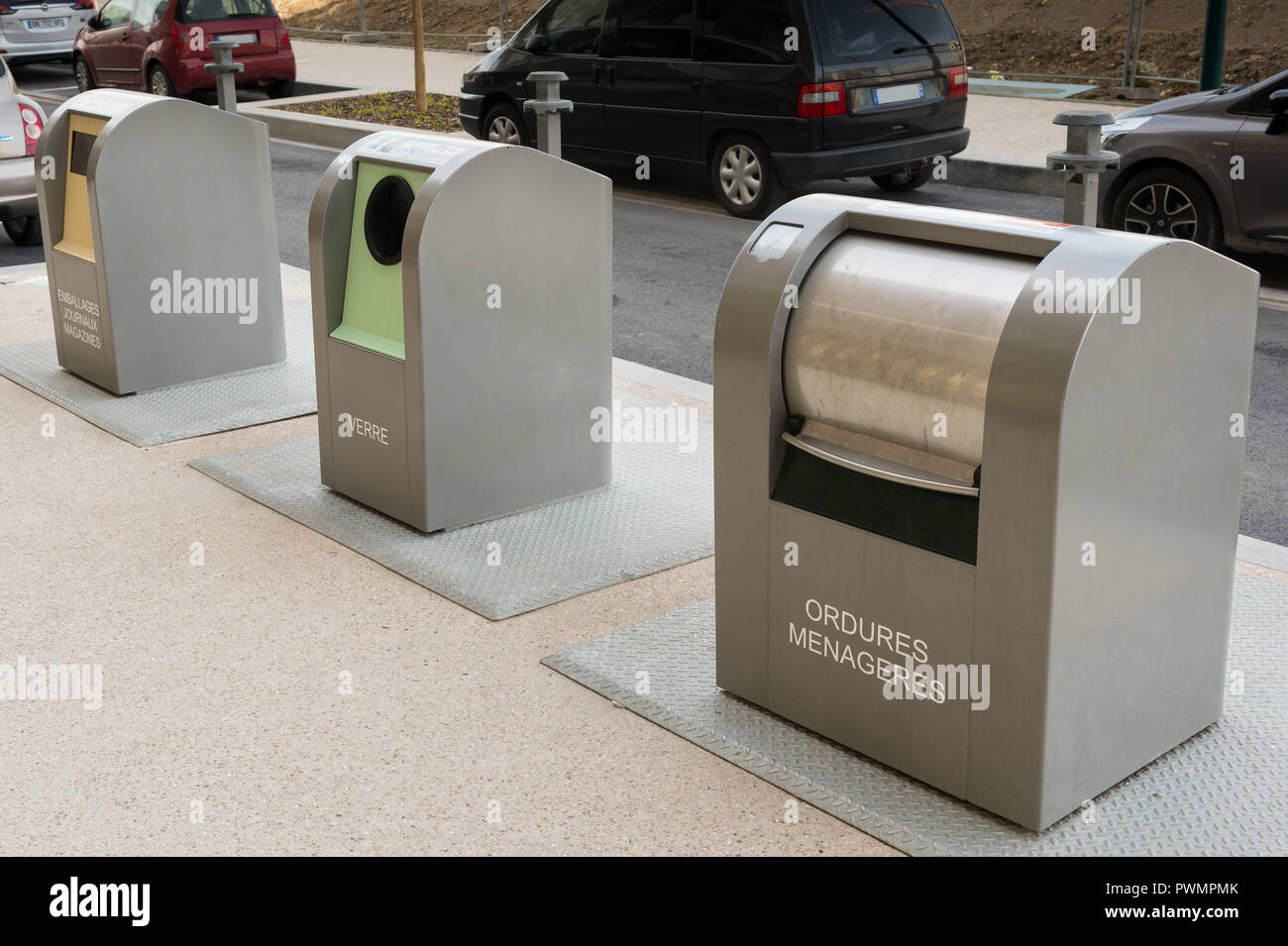 Sorting out garbage containers burried in the street Stock Photo - Alamy