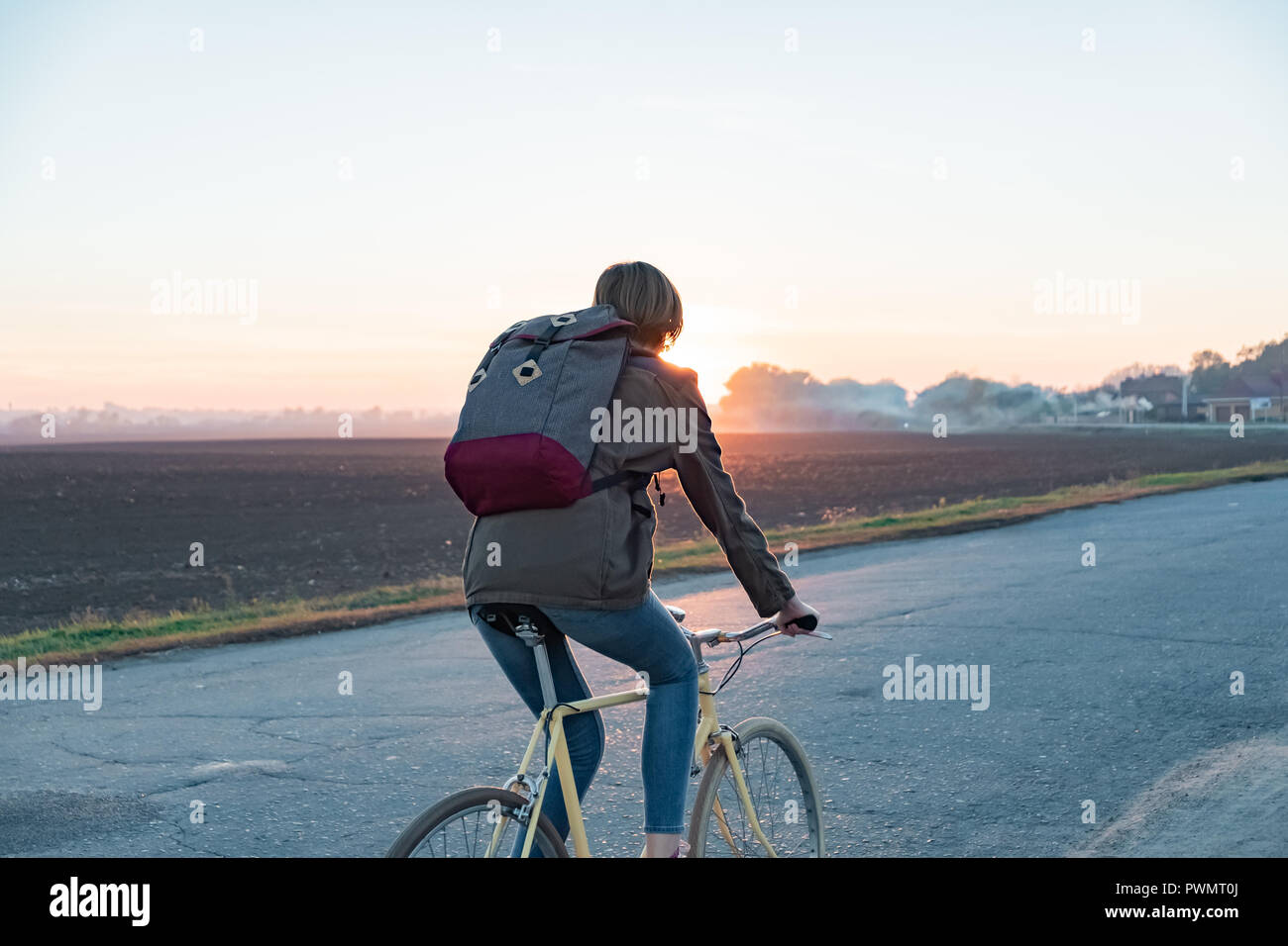 Female commuter riding a bike out of town to a suburban area. Young ...