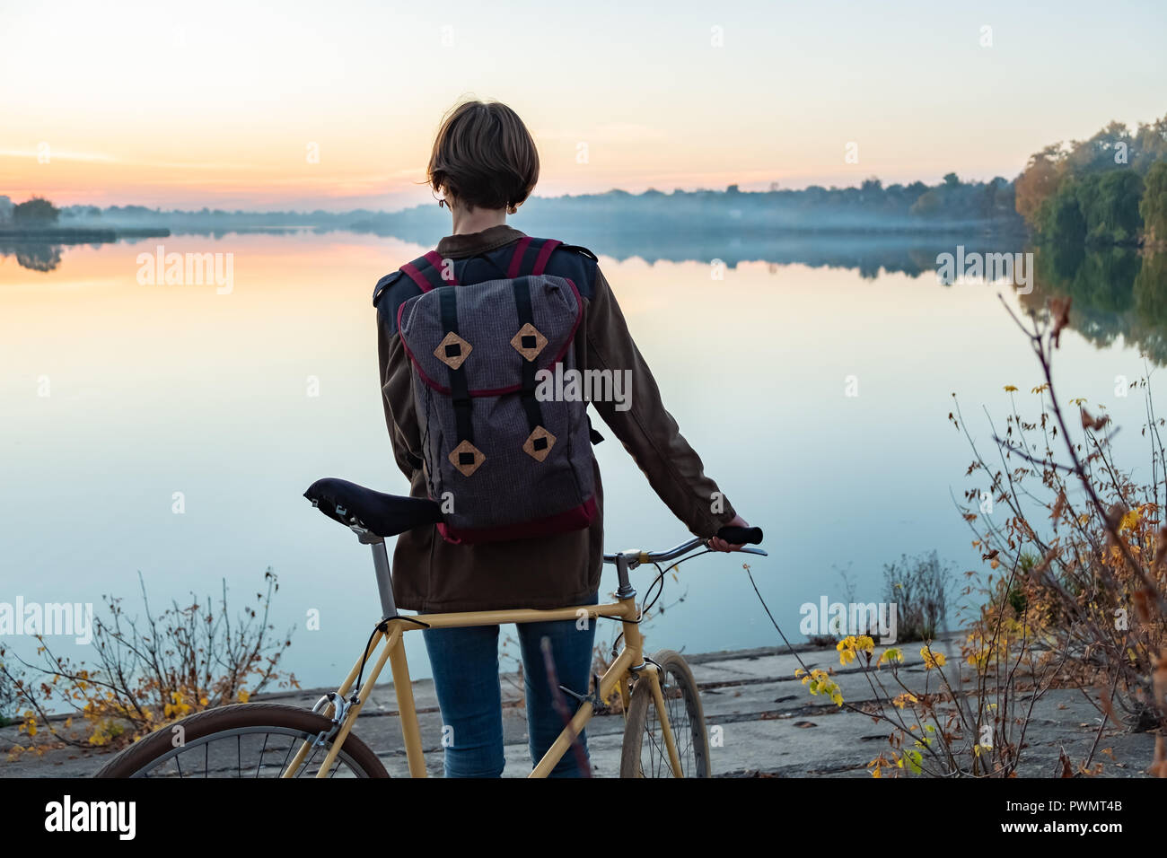 Female cyclist enjoying beautiful blue hour scene by the lake. Woman ...