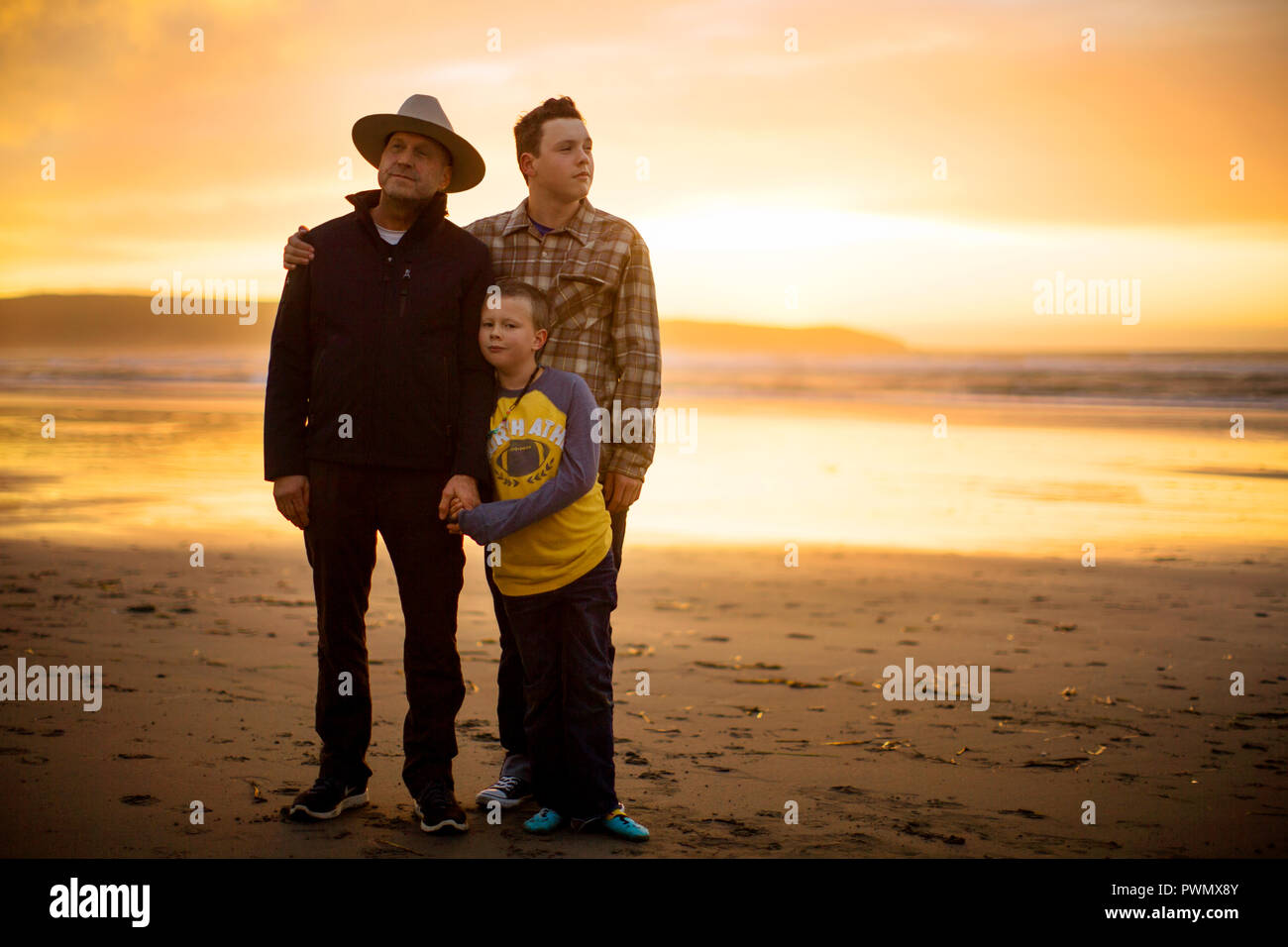 Middle-aged father and his two sons comfort each other as they stand ...