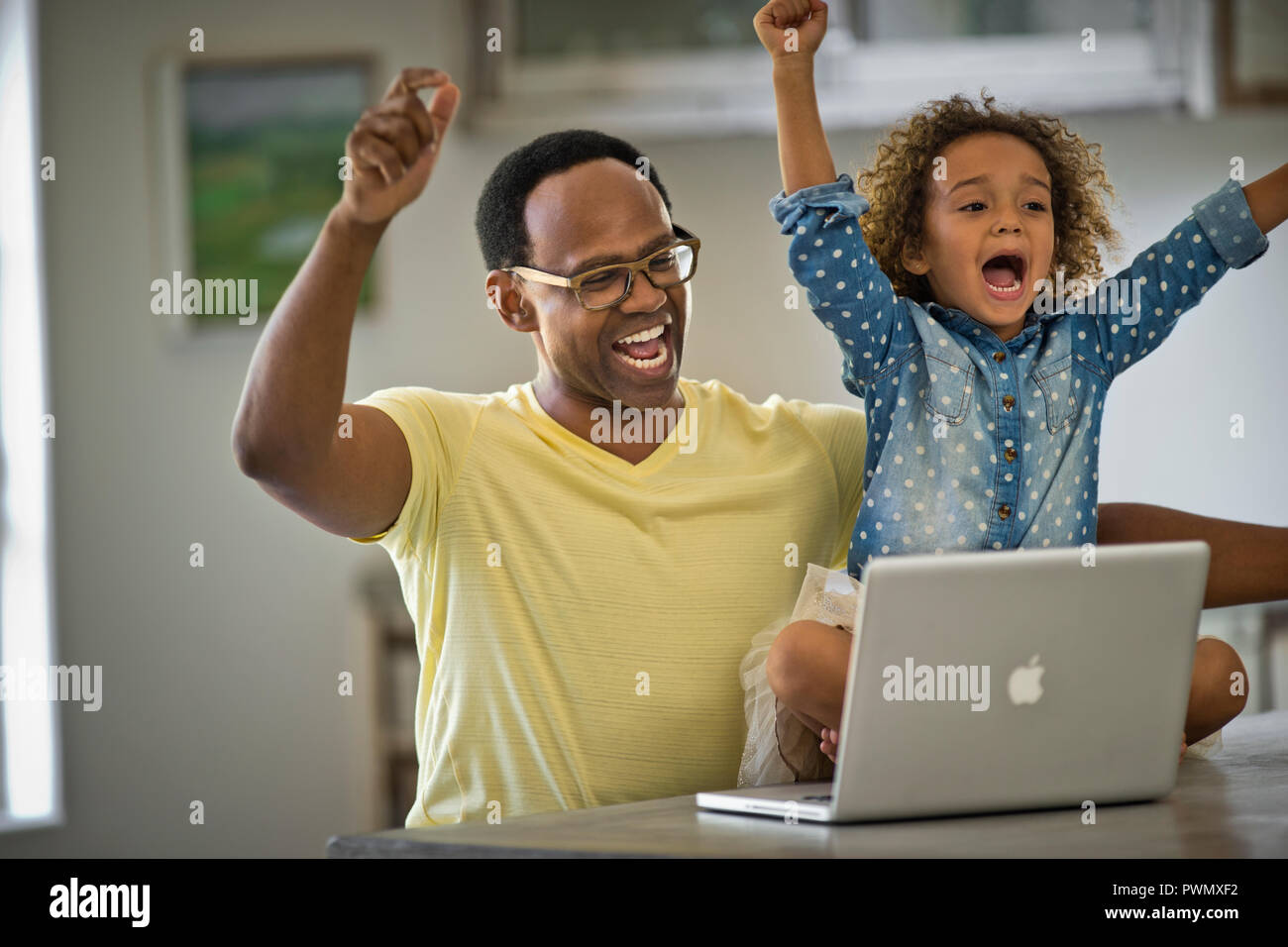 Father and daughter cheering while using the computer Stock Photo - Alamy