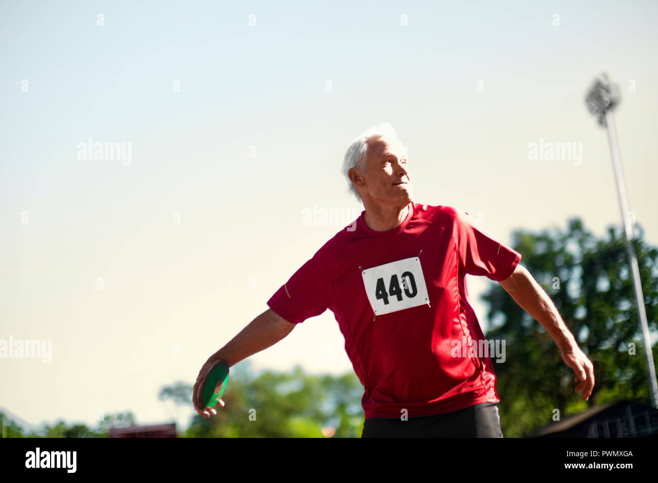 Focused mature man taking aim with a discus Stock Photo - Alamy