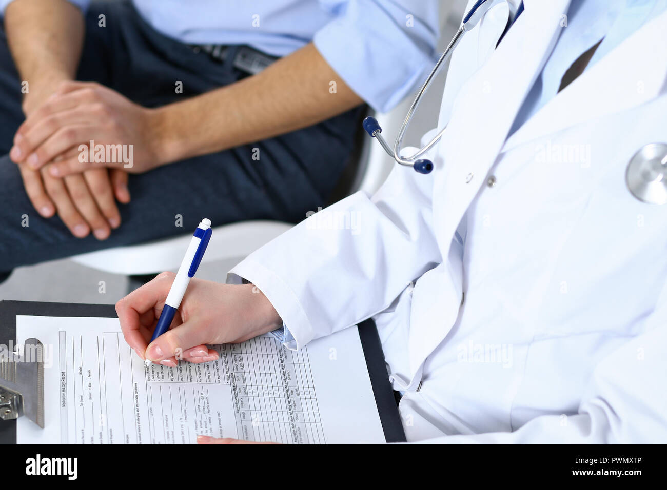 Female doctor holding application form while consulting man patient in ...