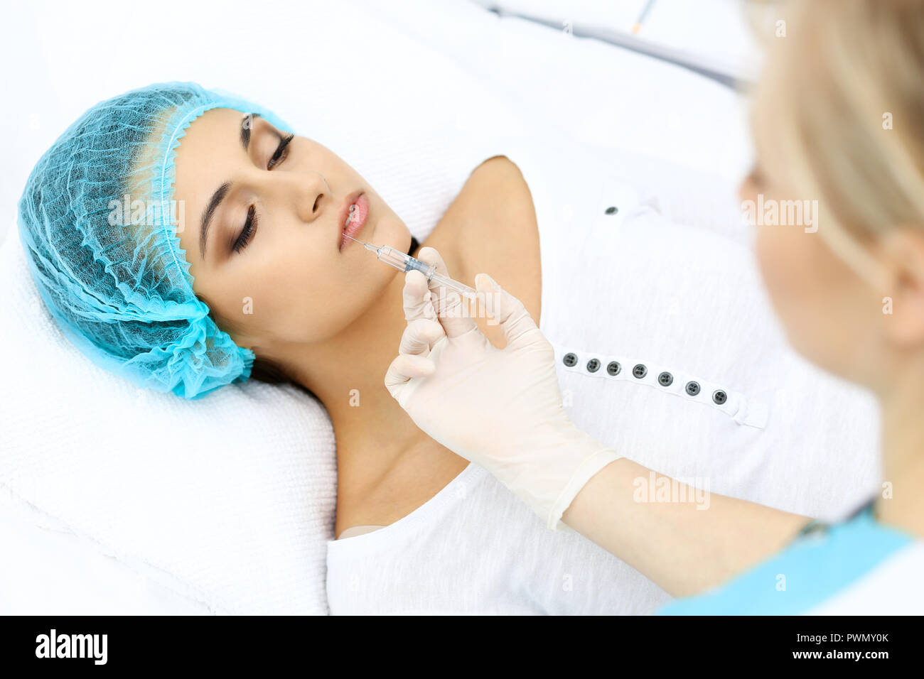 Professional cosmetologist making injection in face, lips. Young woman ...