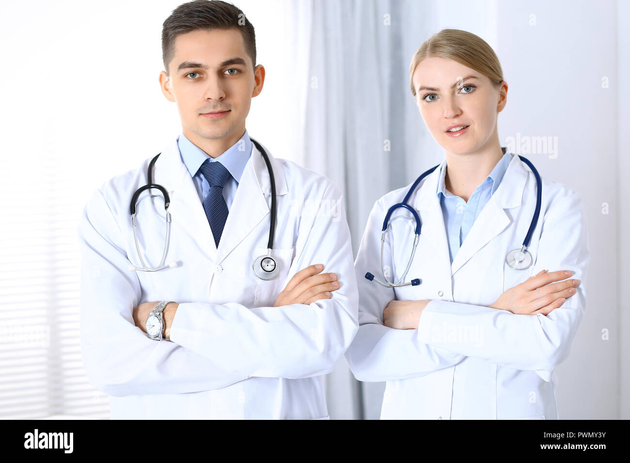 Doctors standing straight with arms crossed in hospital. Physicians ...