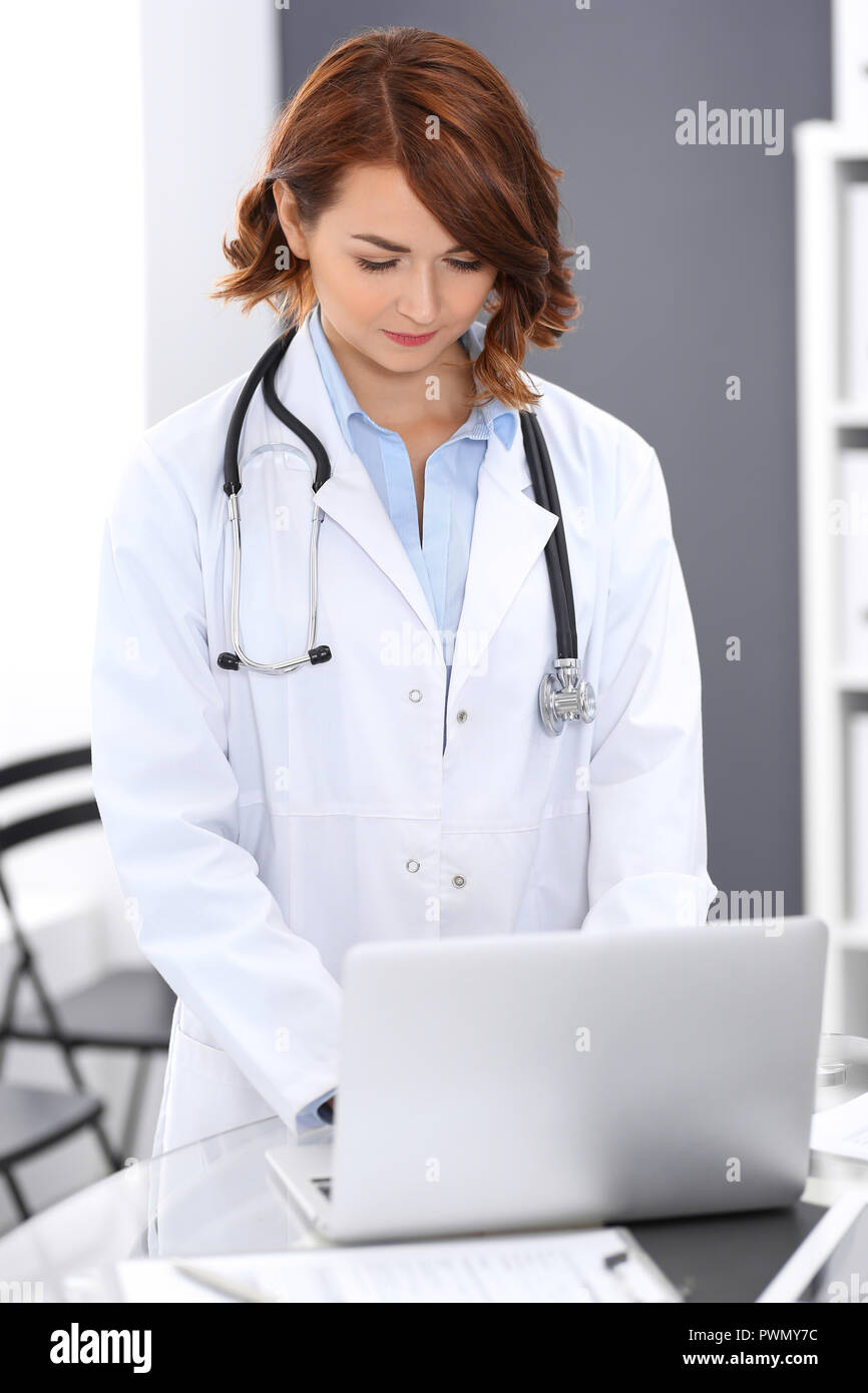 Happy doctor woman at work. Portrait of female physician using laptop ...