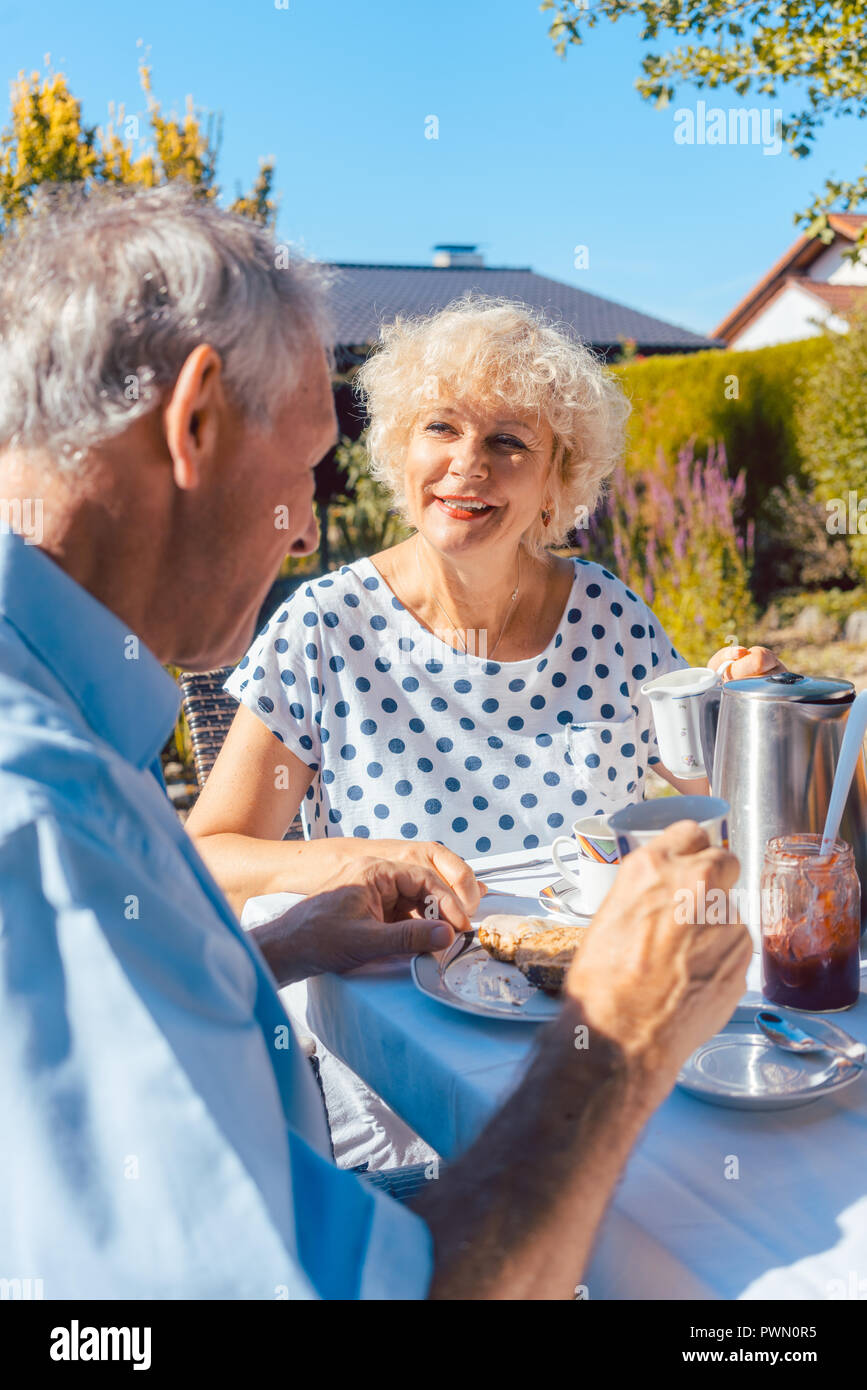 Happy elderly couple eating breakfast in their garden outdoors Stock ...