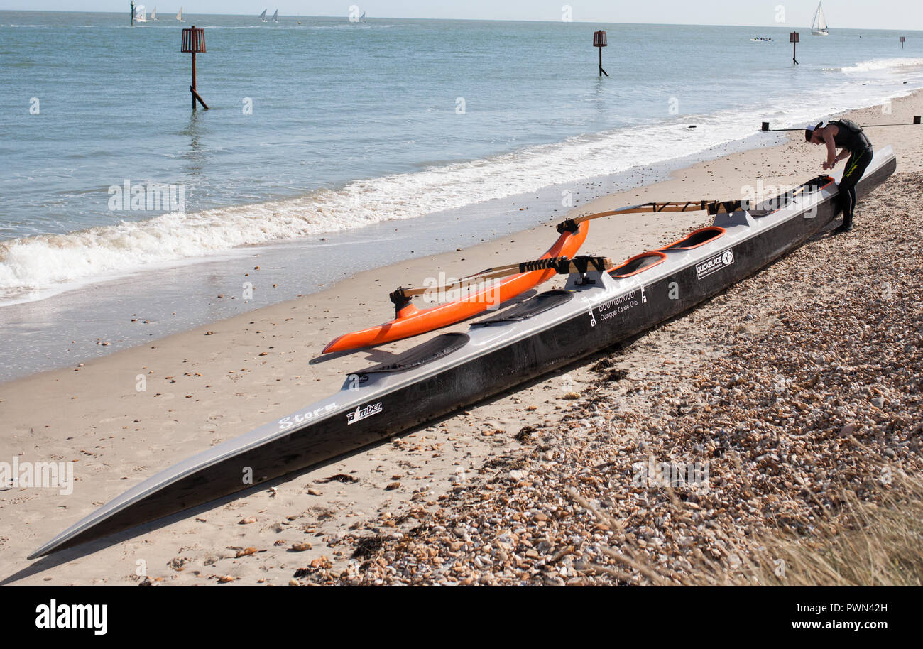 Dragon boat on the beach being prepared by one guy for a team race ...