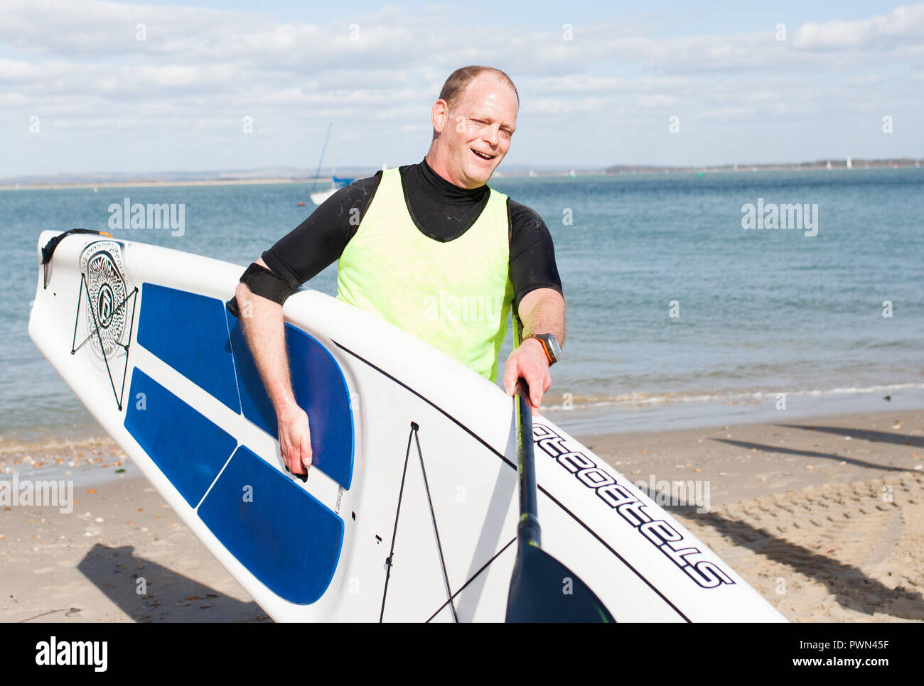 Man carrying paddle board Stock Photo - Alamy