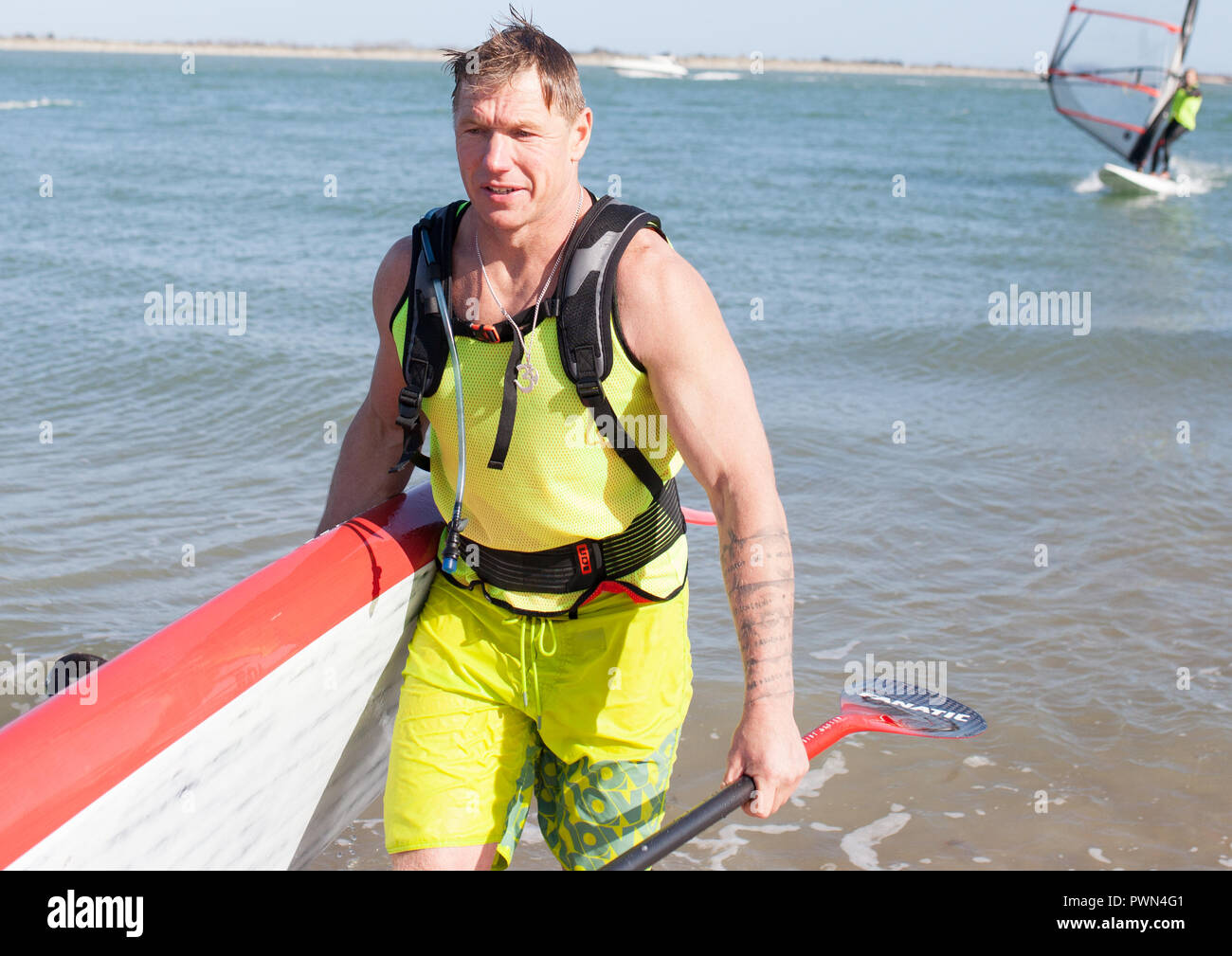 Man carrying paddle board to finish line Stock Photo - Alamy