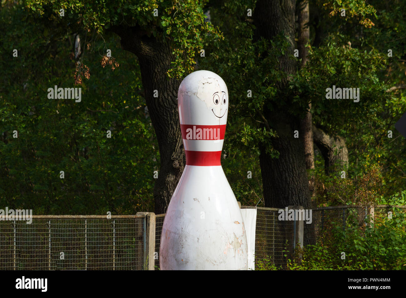 Bowling cone with white and red stripes in front of green background ...