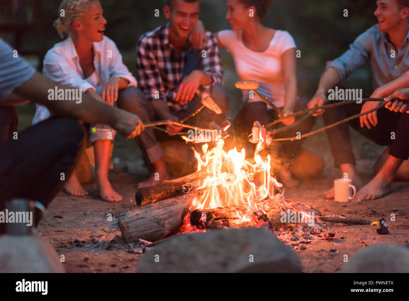 a group of happy young friends relaxing and enjoying summer evening ...