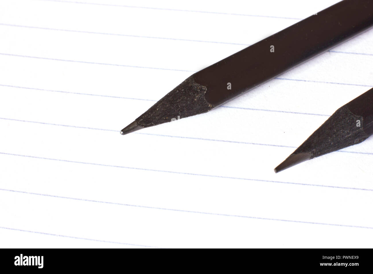 Black pencils on a white line paper Stock Photo - Alamy