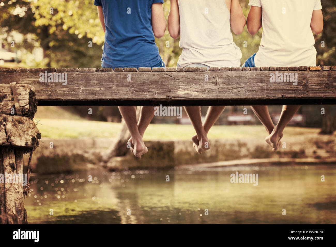 group of people sitting at wooden bridge over the river with a focus on ...