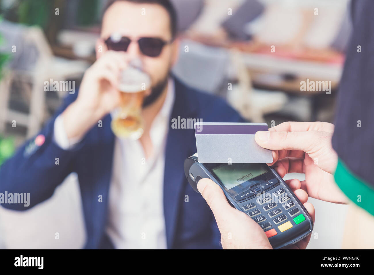 Paying with credit card in cafe. Businessman drinking beer in the ...