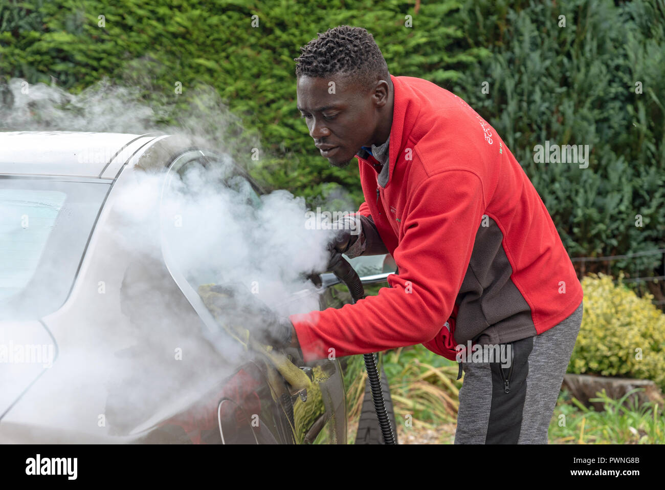 Man steam cleaning a luxury car on a home visiting valet service ...