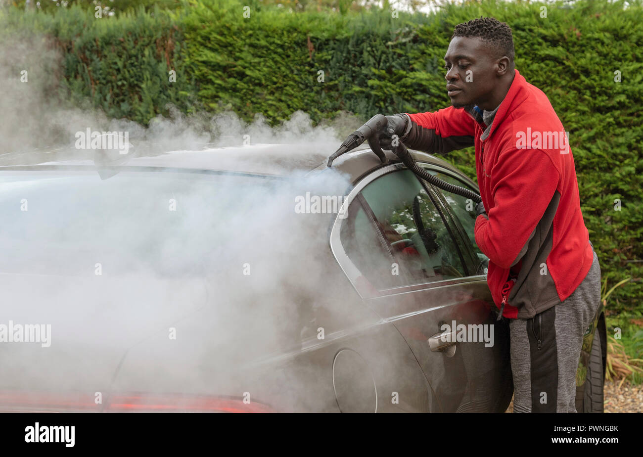 Man steam cleaning a luxury car on a home visiting valet service ...