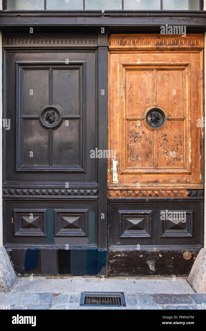 Building entrance with two wooden doors. One restored, one unrestored ...