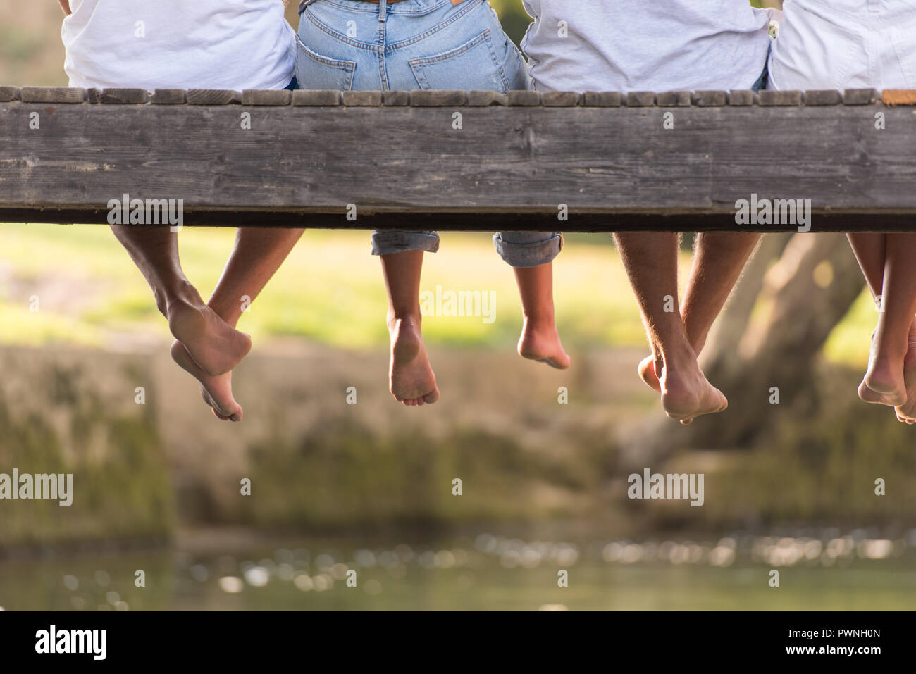 group of people sitting at wooden bridge over the river with a focus on ...