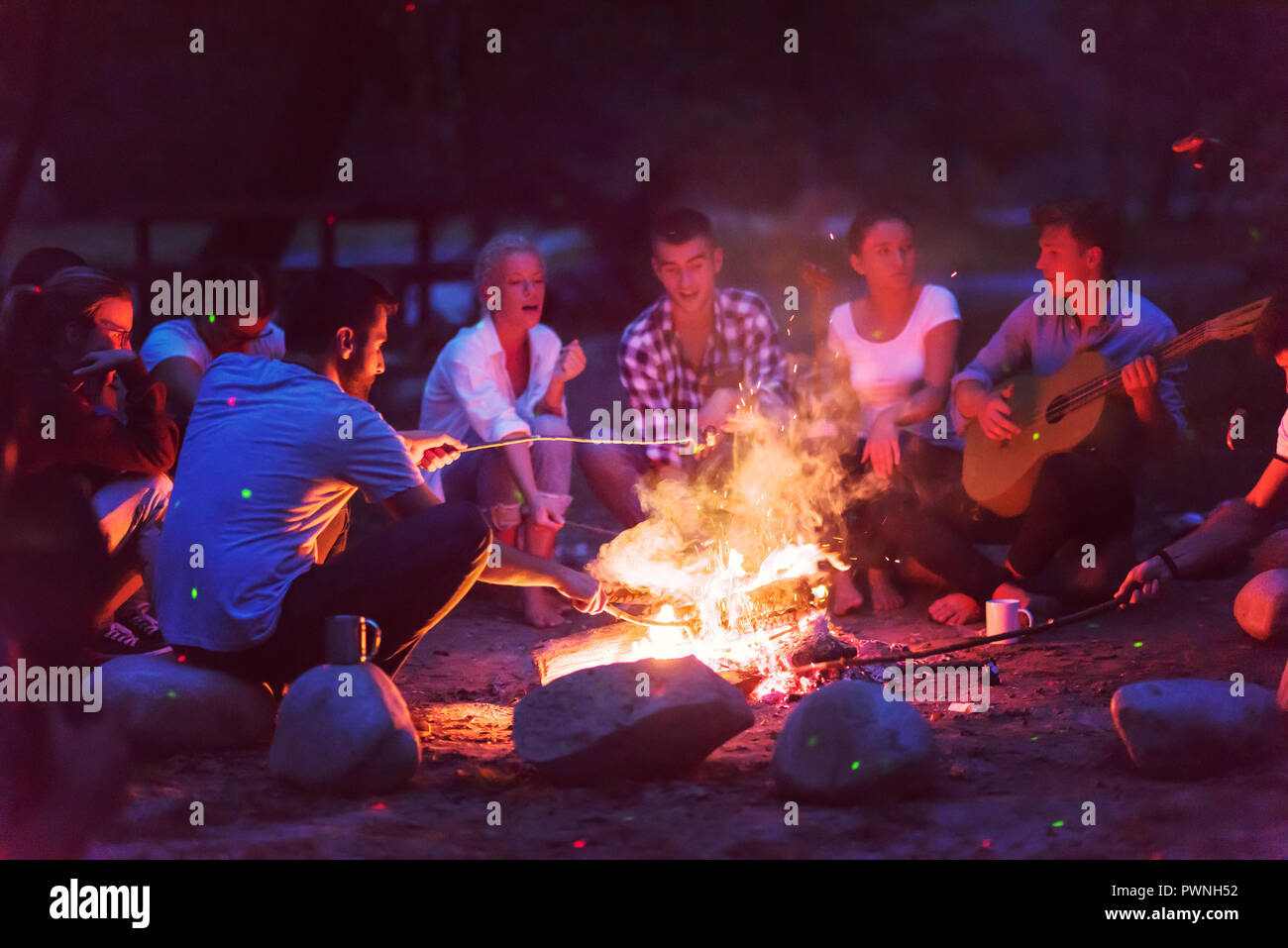 a group of happy young friends relaxing and enjoying summer evening ...