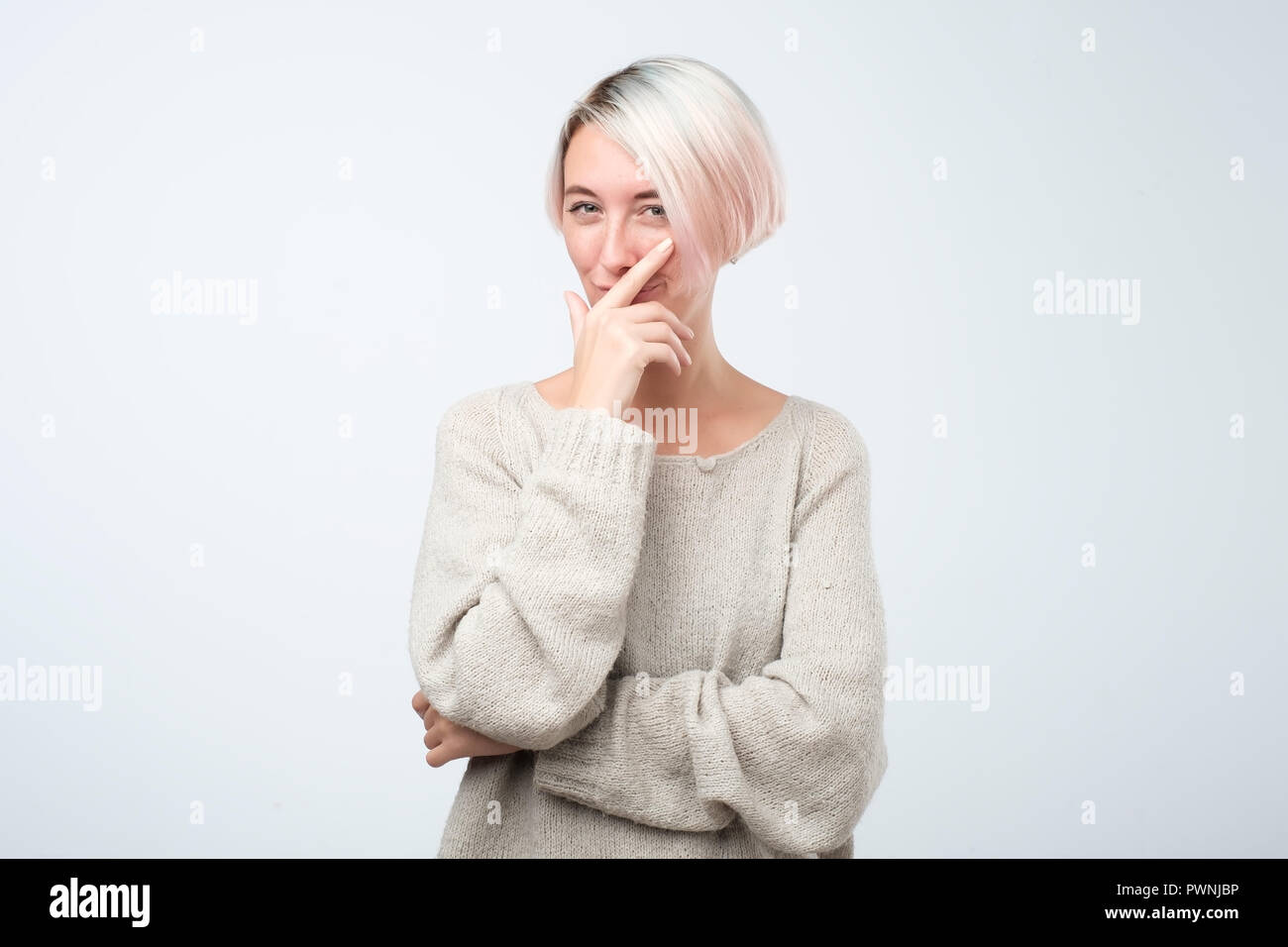 Cunning beautiful woman with dyed short hair looking holding hand under ...
