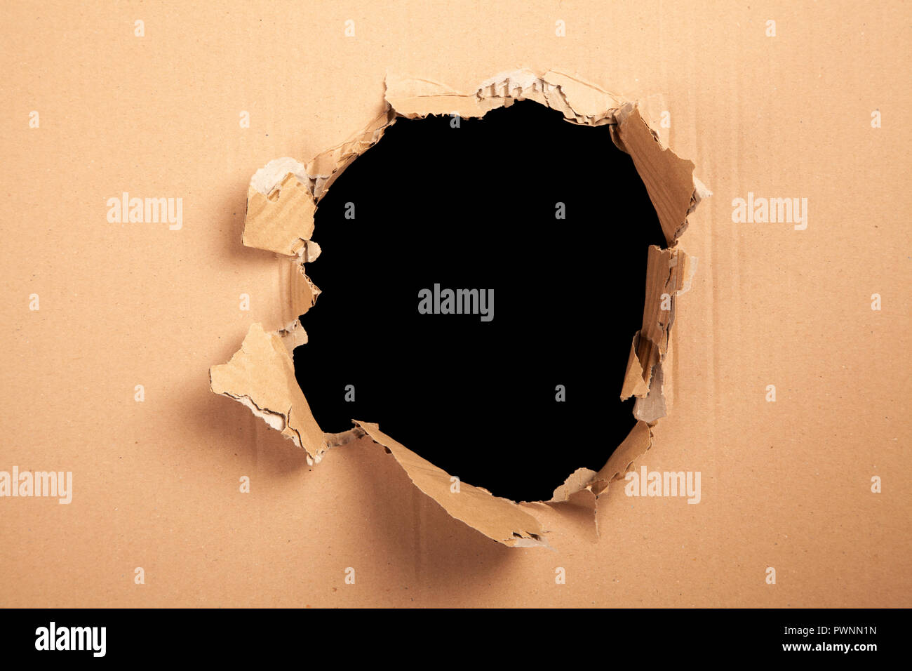 Cardboard with a hole - black background Stock Photo - Alamy