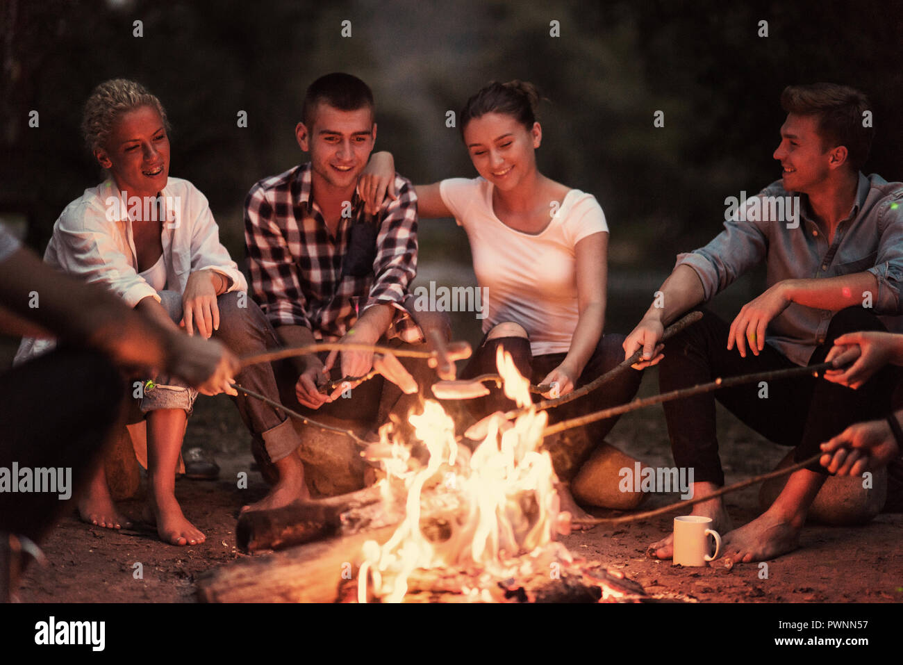 a group of happy young friends relaxing and enjoying summer evening ...