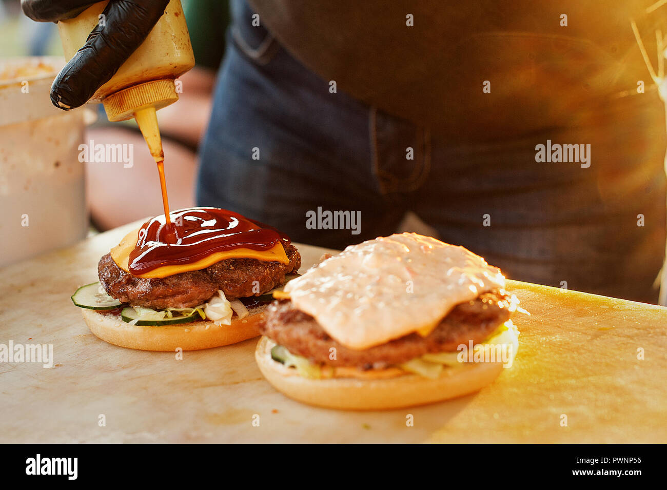 The chef prepares a burger in the open air kitchen. Street fast food ...