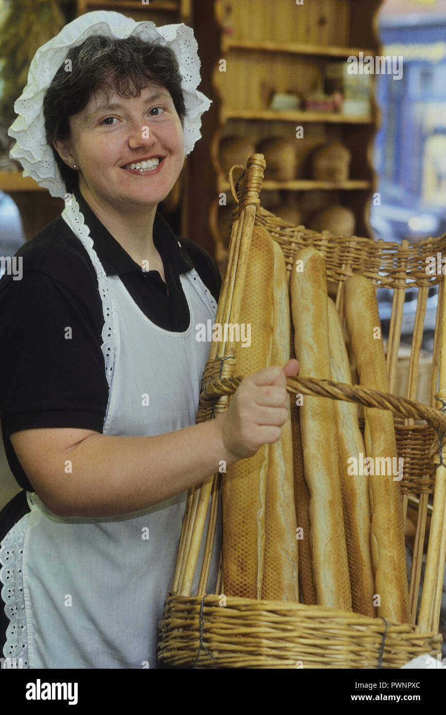Bakery server holding a wicker basket of baguettes. England, UK Stock ...