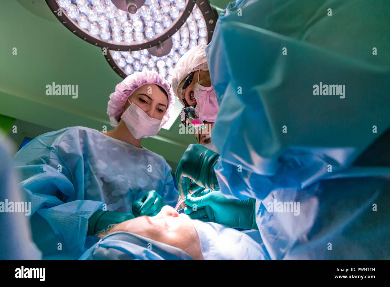 Surgeon and his assistant performing cosmetic surgery on nose in ...