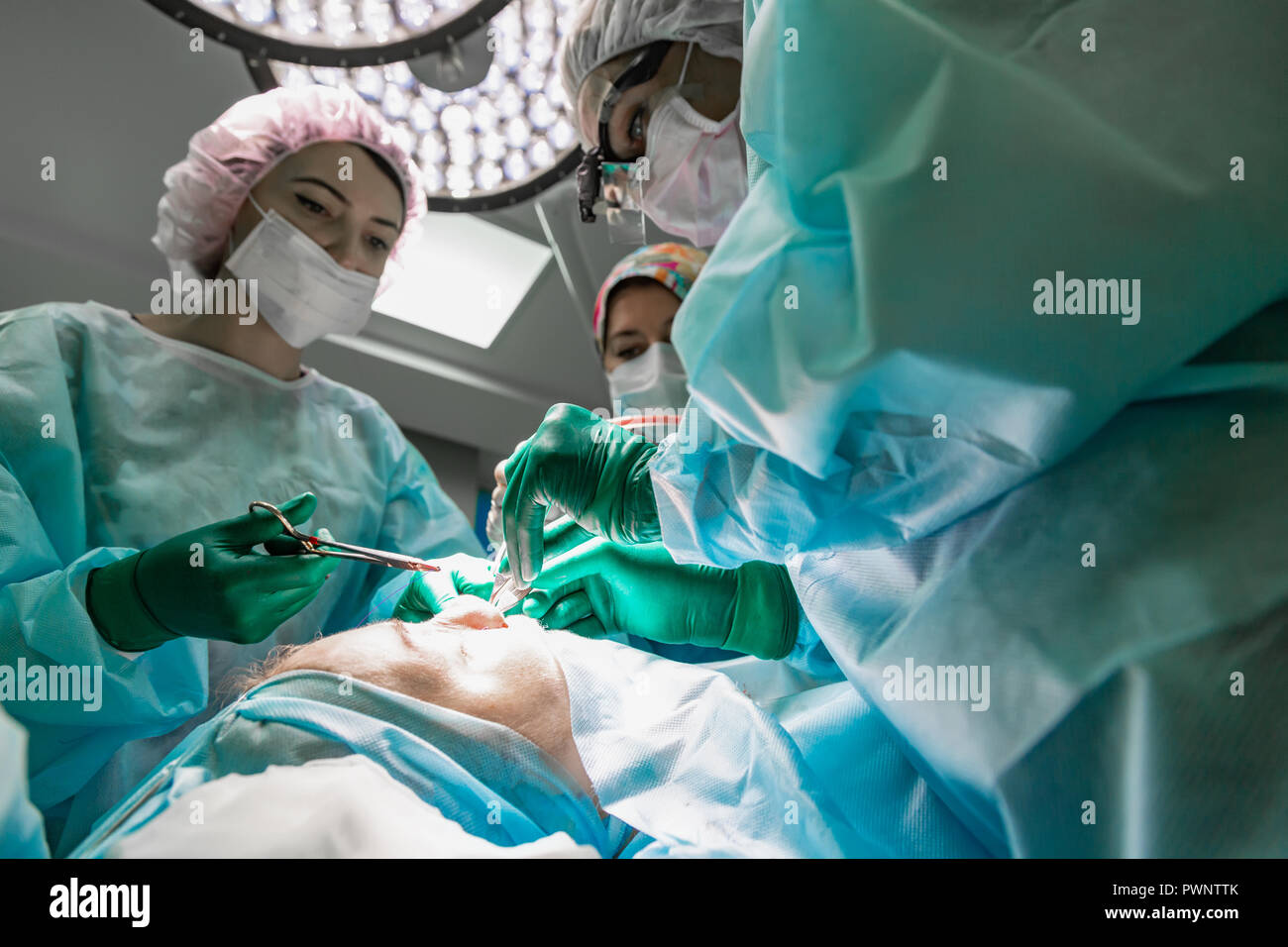 Surgeon and his assistant performing cosmetic surgery on nose in ...