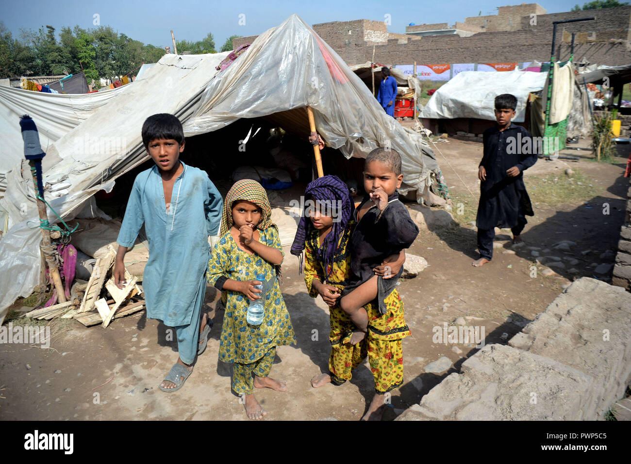 Peshawar. 17th Oct, 2018. Children play outside their shelters at a ...