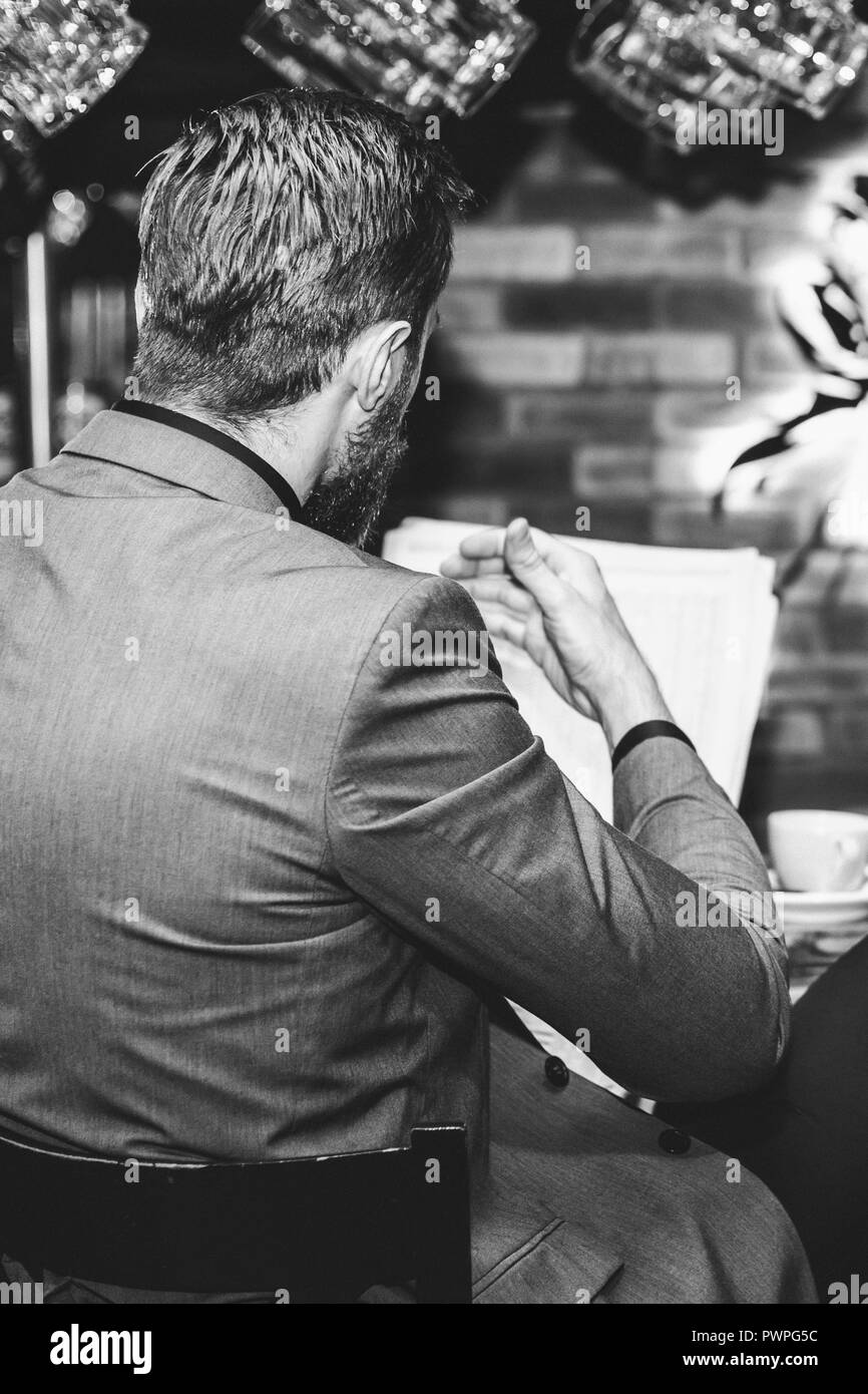 Back view portrait of a young bearded businessman sitting at the bar ...