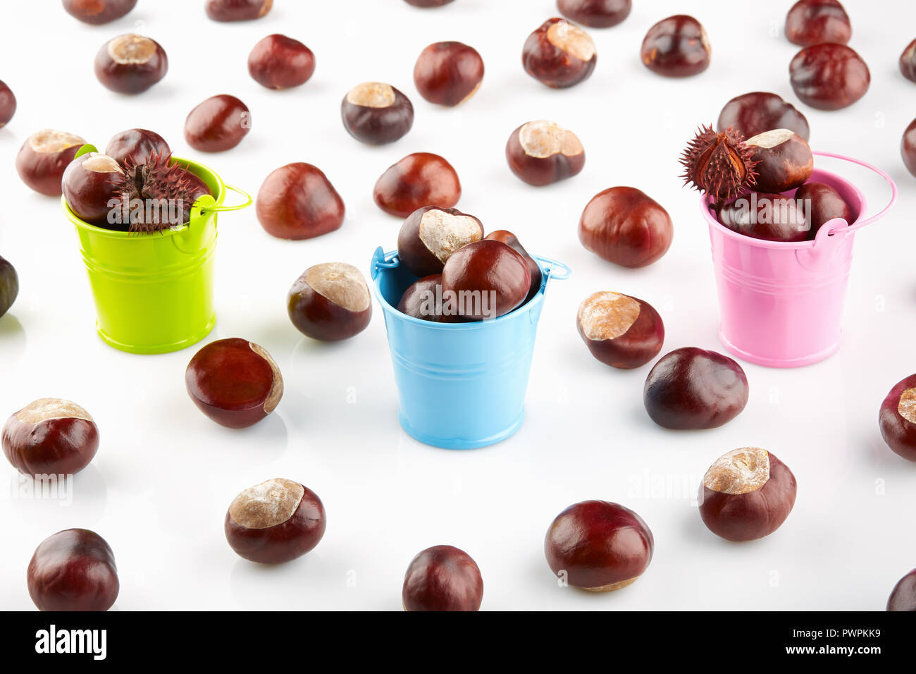 Colorful buckets with chestnuts and peeled horse-chestnuts on white ...