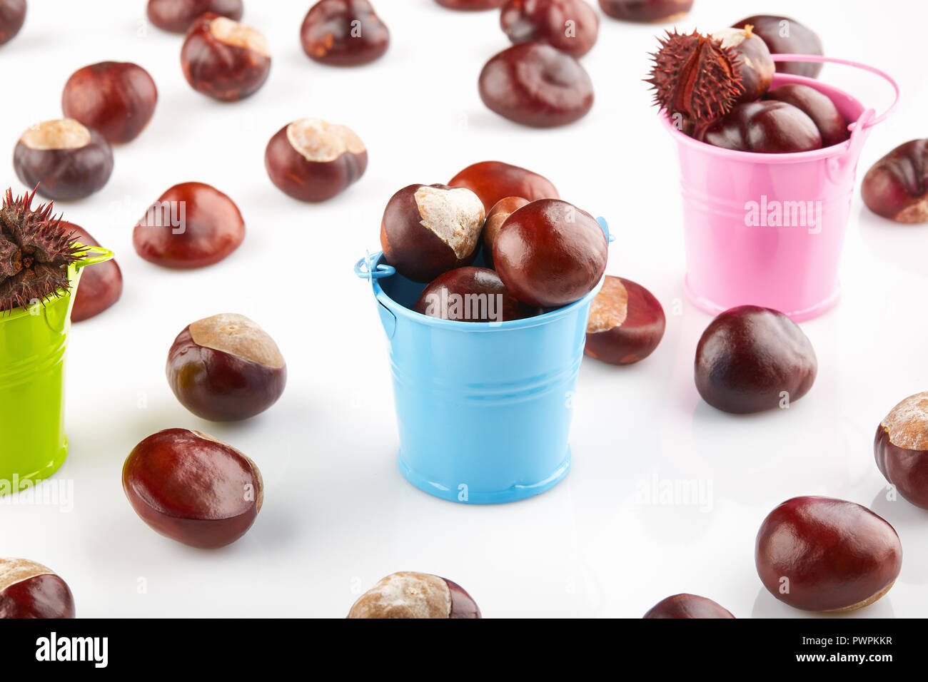 Colorful buckets with chestnuts and peeled horse-chestnuts on white ...