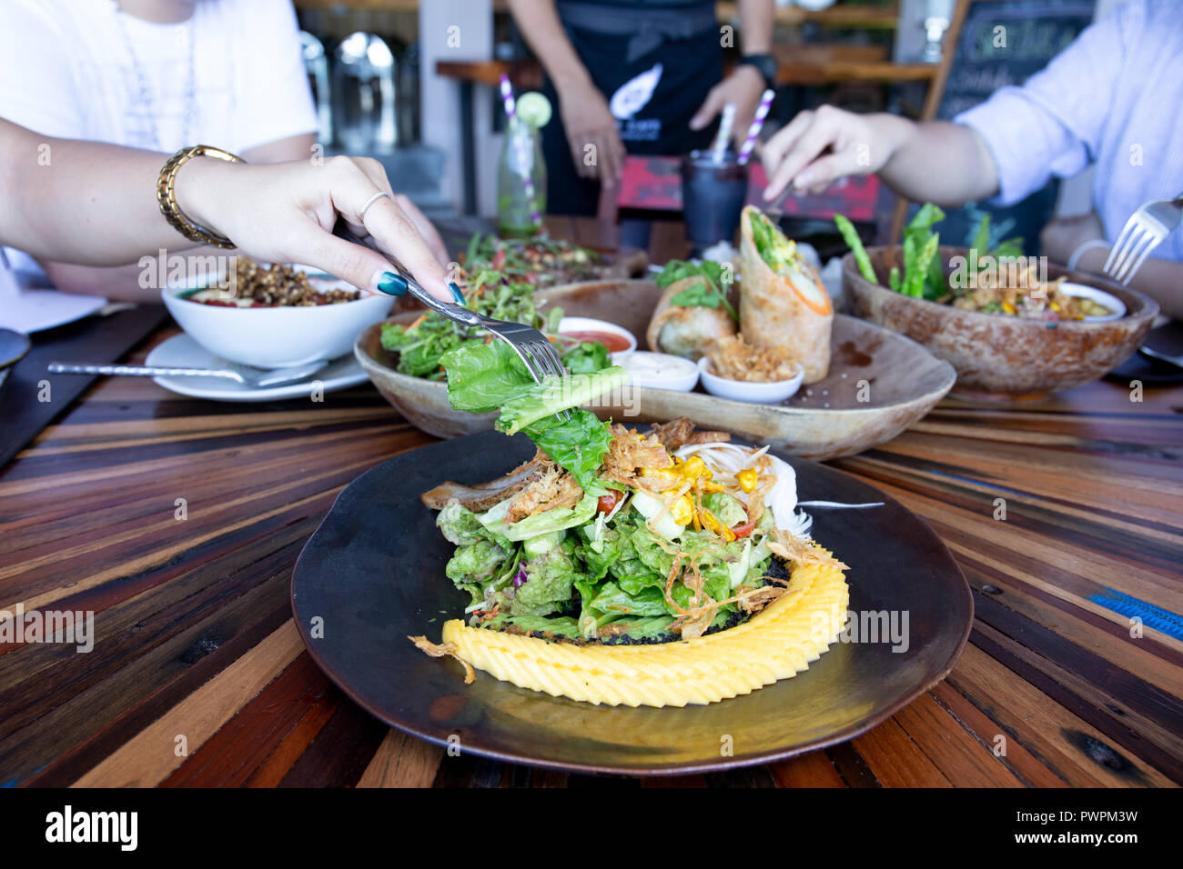 Woman hand with fork eating vegetables salad with friends Stock Photo ...