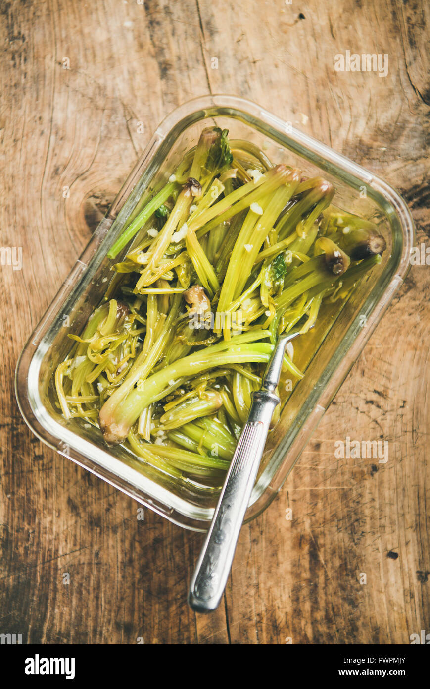 Flat-lay of pickled spinach stem salad over wooden table background ...