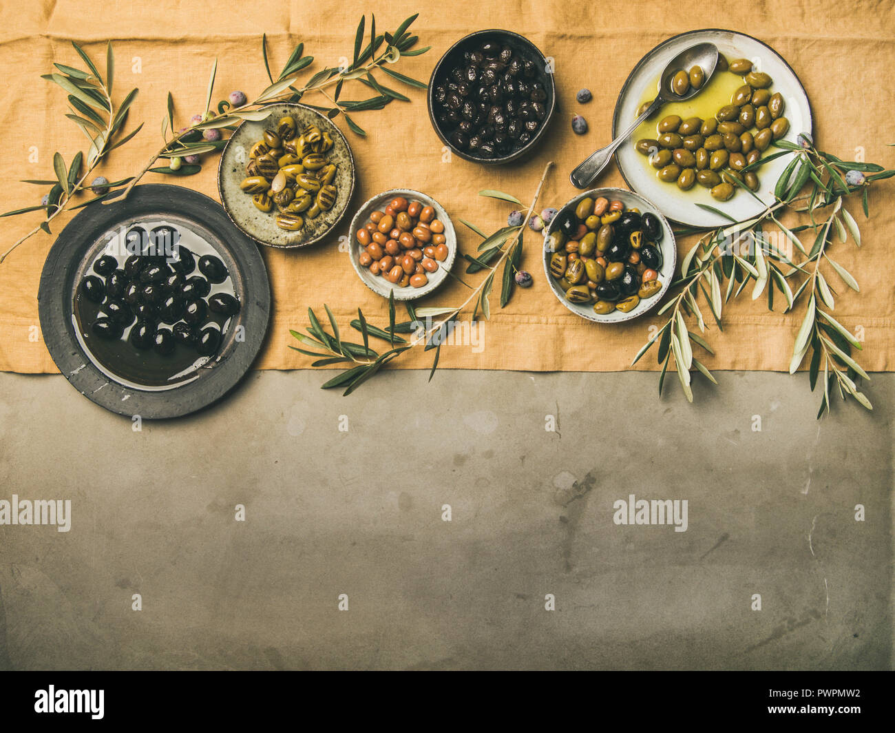 Flat-lay of various kinds of Mediterranean pickled olives in plates and ...