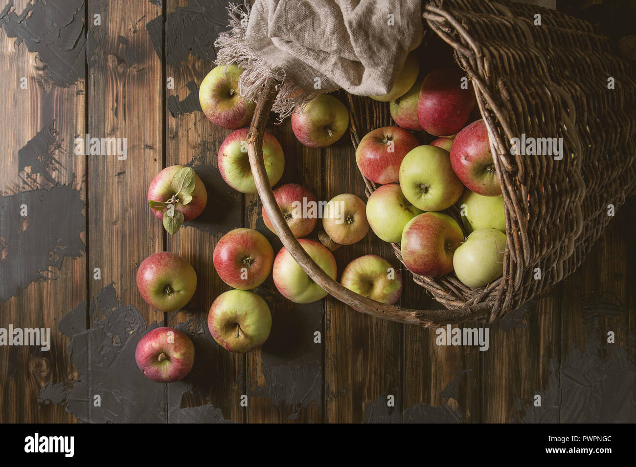 Ripe gardening green red apples in old basket with cloth over dark ...