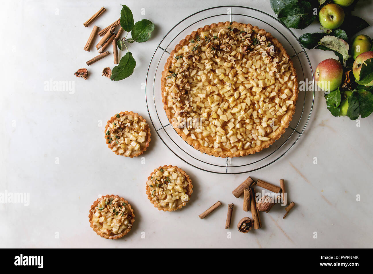 Homemade sweet apple shortbread tart on cooling rack and tartlets with ...