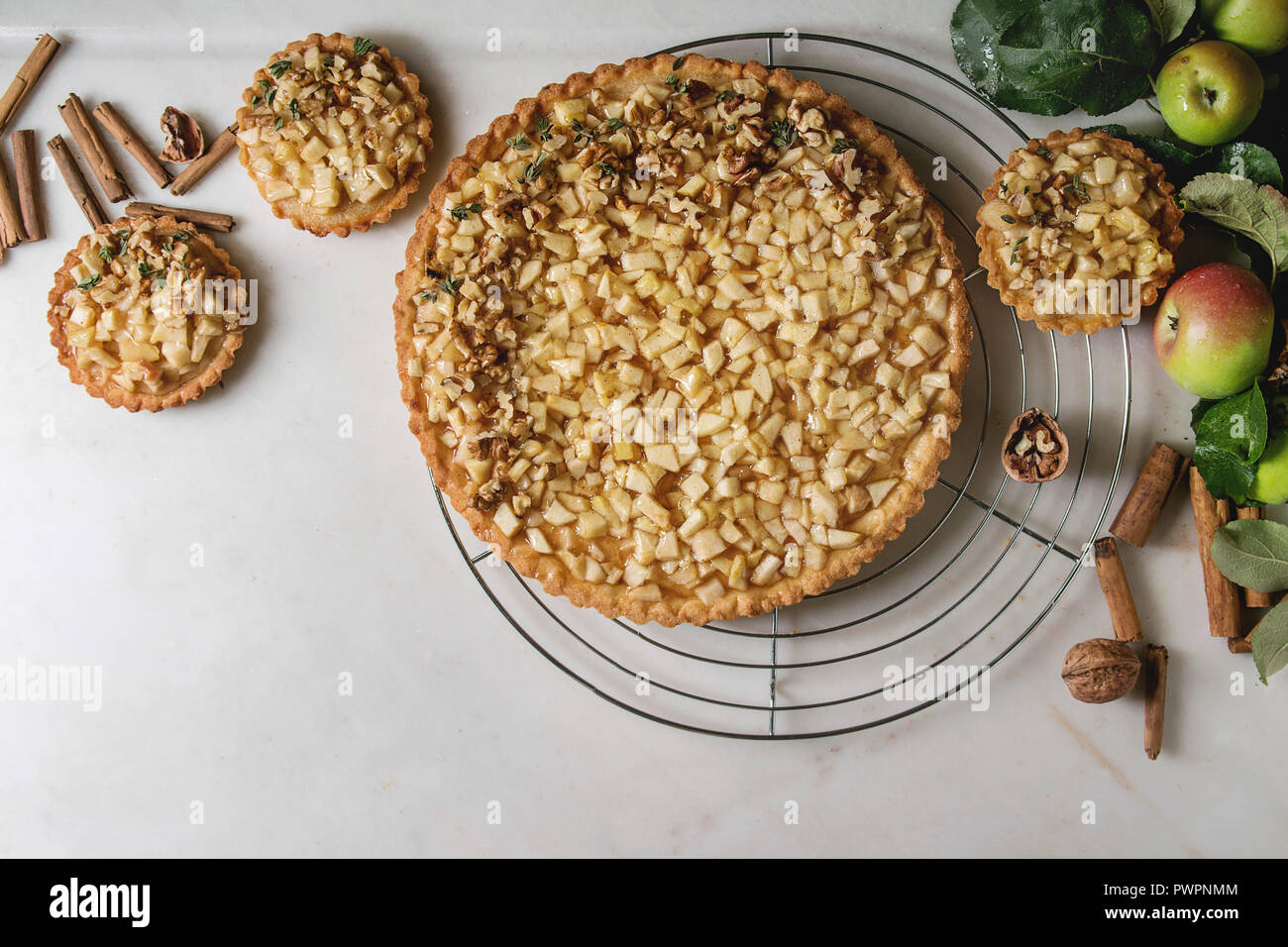 Homemade sweet apple shortbread tart on cooling rack and tartlets with ...