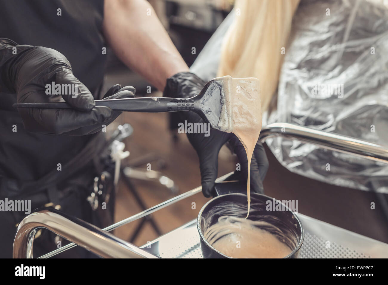 Stylist preparing a hair dye in a container, hairdresser salon concept ...