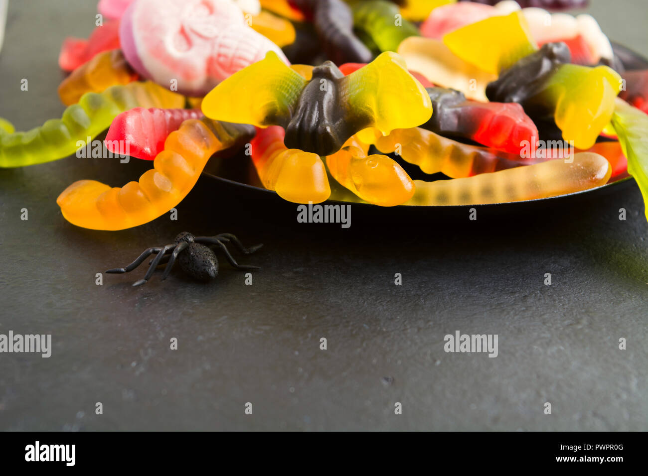 Plate of various Halloween candies and spider on black backgroundwith ...