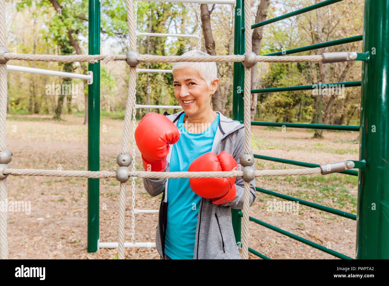 Portrait Of Happy Fit Senior Woman With Boxing Glove At Outdoor Gym In ...