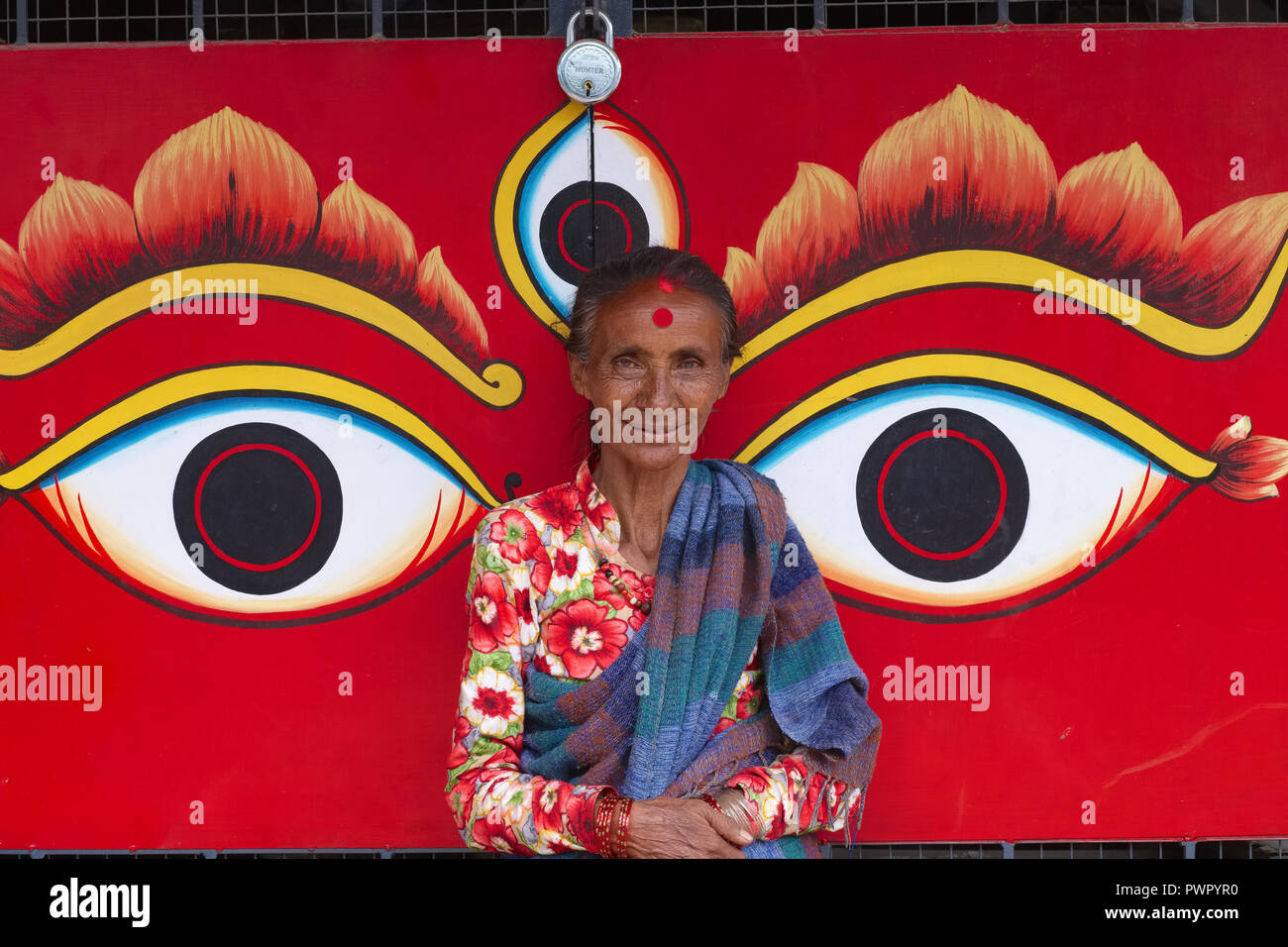 A Nepalese woman at a Hindu shrine, a red tika mark on her forehead ...