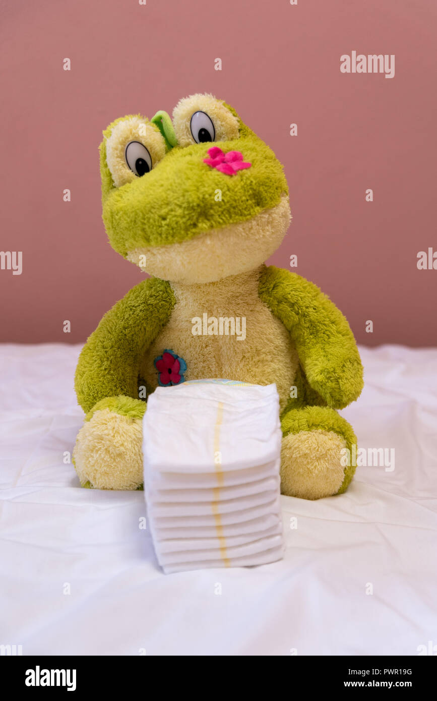 Green frog toy and diapers Stock Photo - Alamy