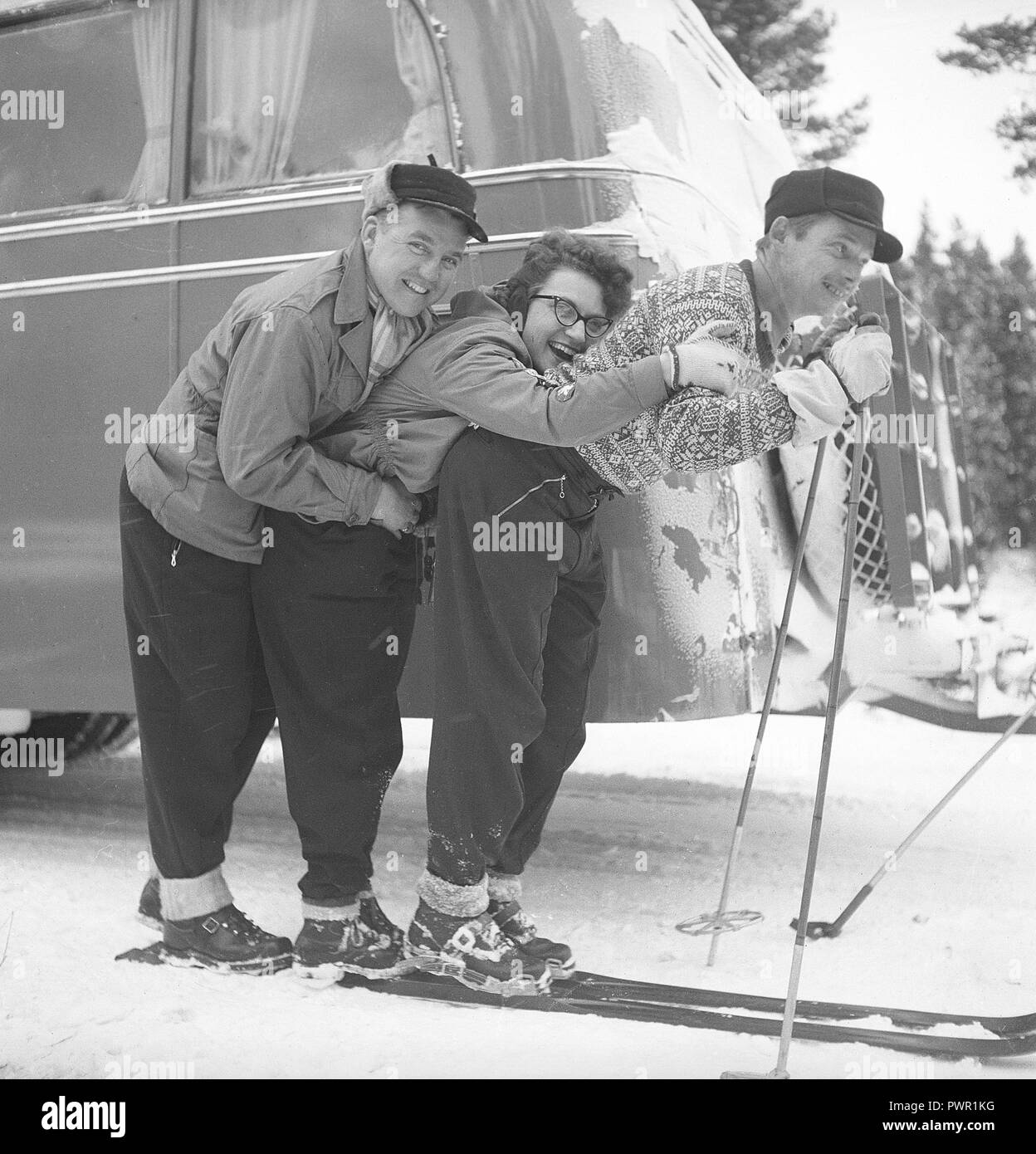 Winter in the 1940s. Two men and a woman is standing on one pair of ...