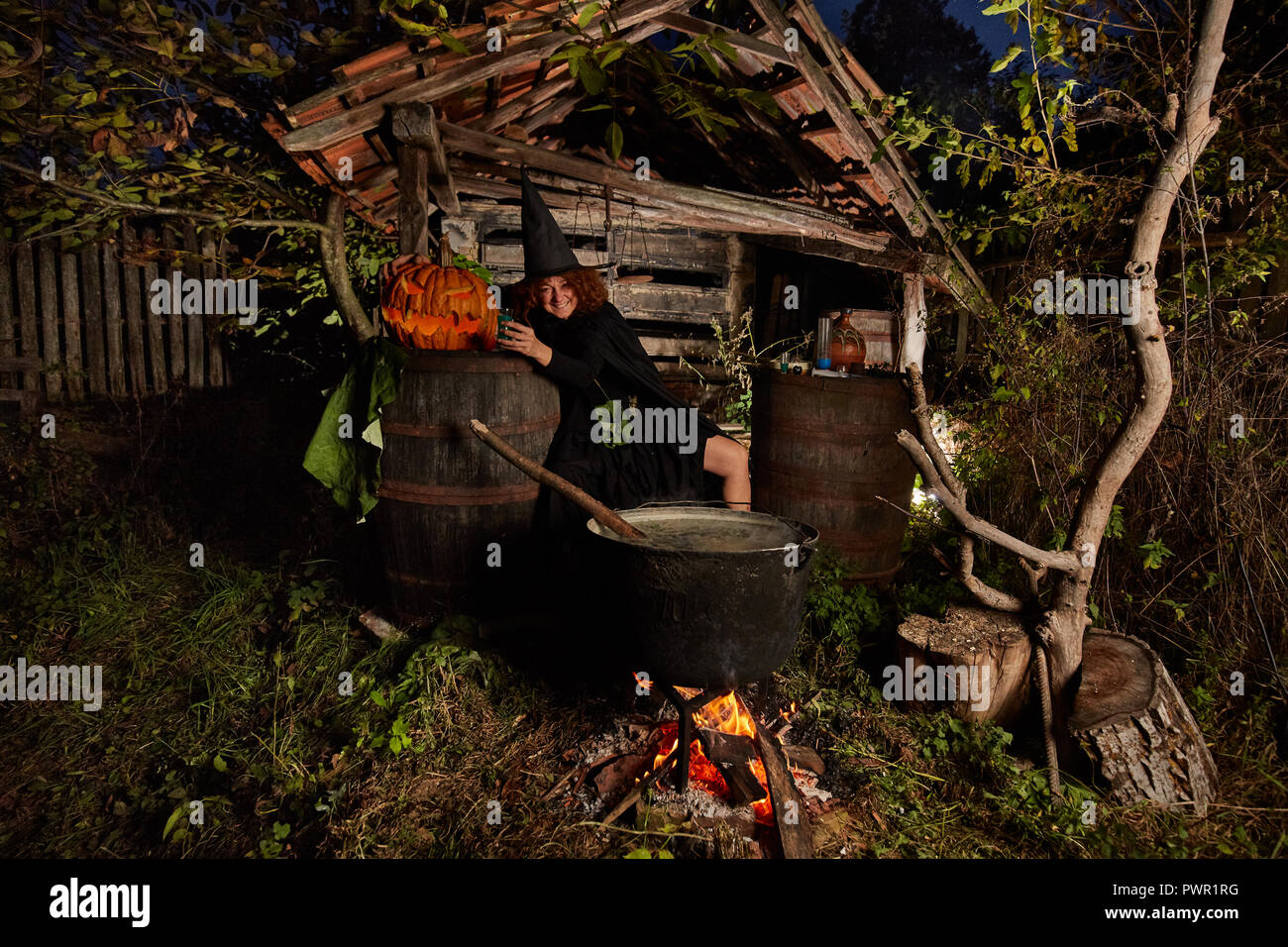 Witch boiling spells in a cast iron black pot in her shed Stock Photo ...